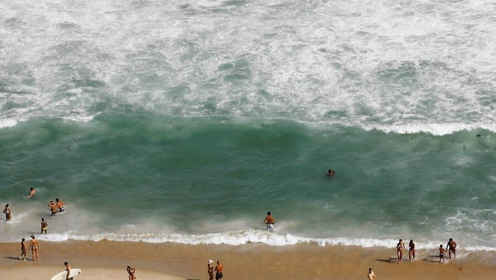 Praia cheia em domingo de sol